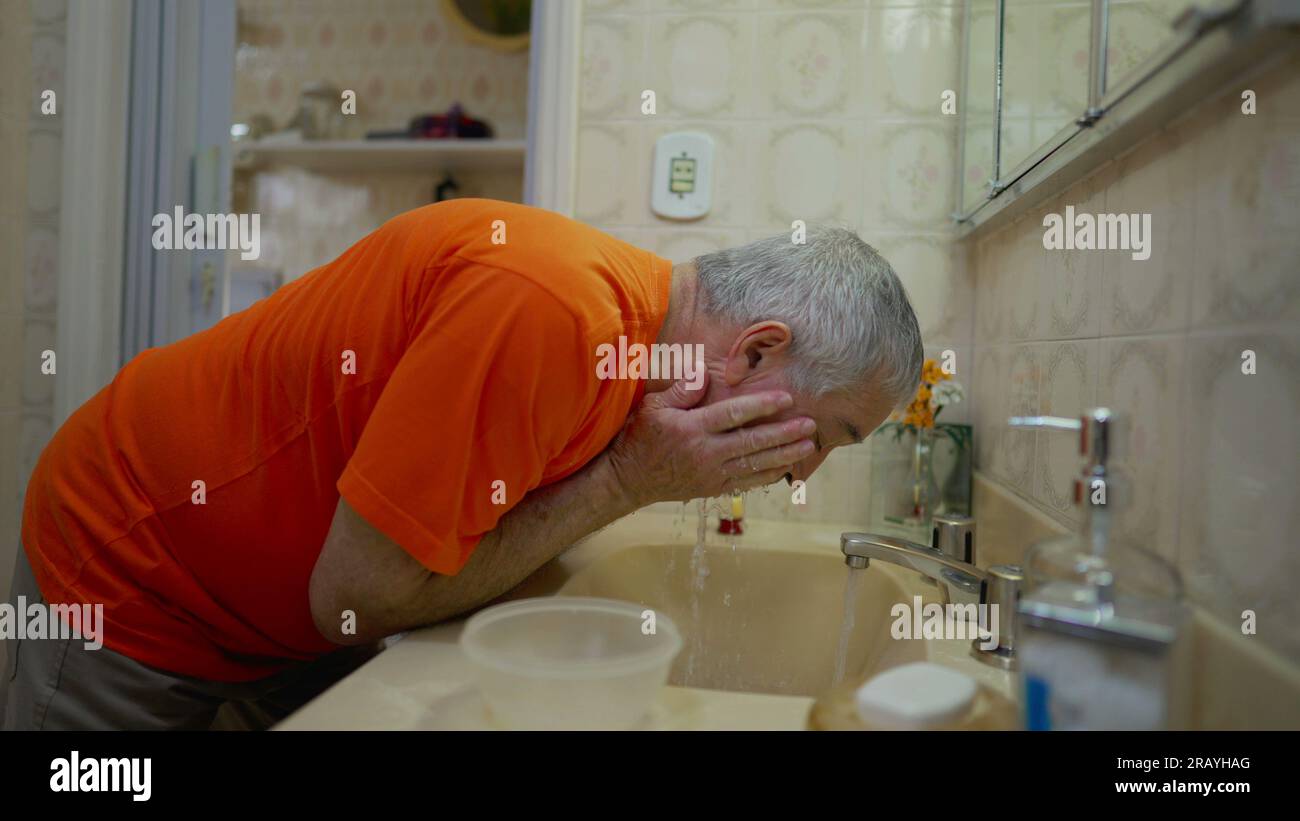 Senior man washing face in bathroom, domestic lifestyle morning routine ...