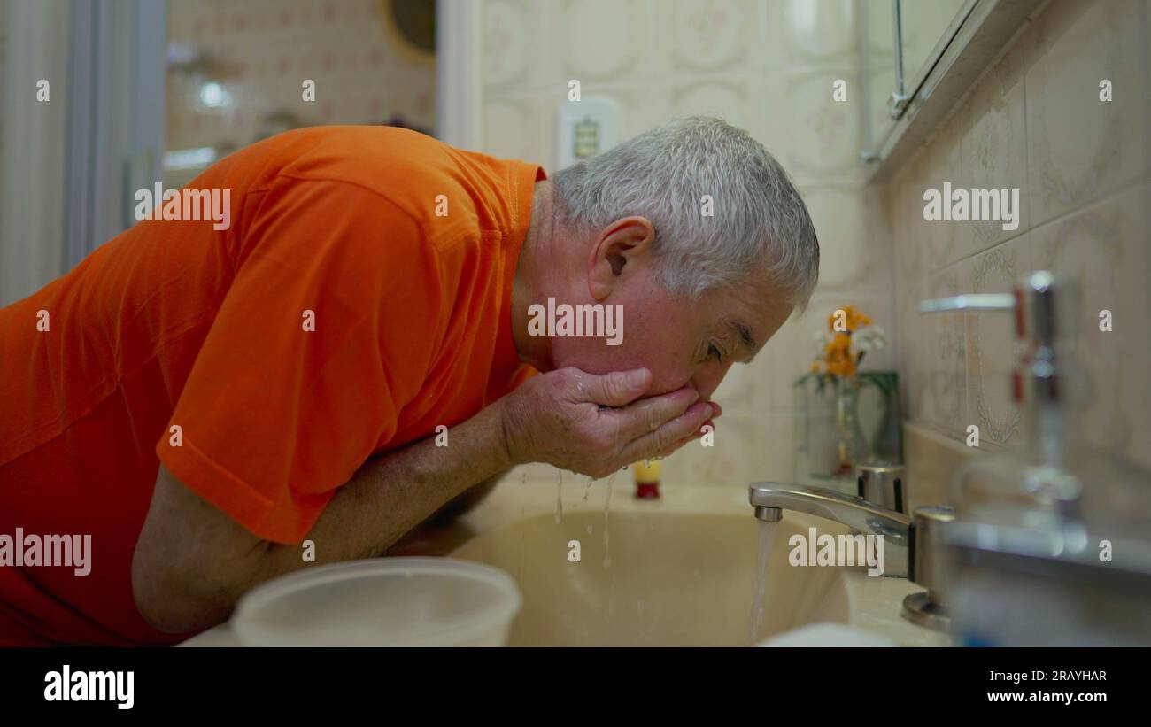 Senior man washing face in bathroom, domestic lifestyle morning routine ...