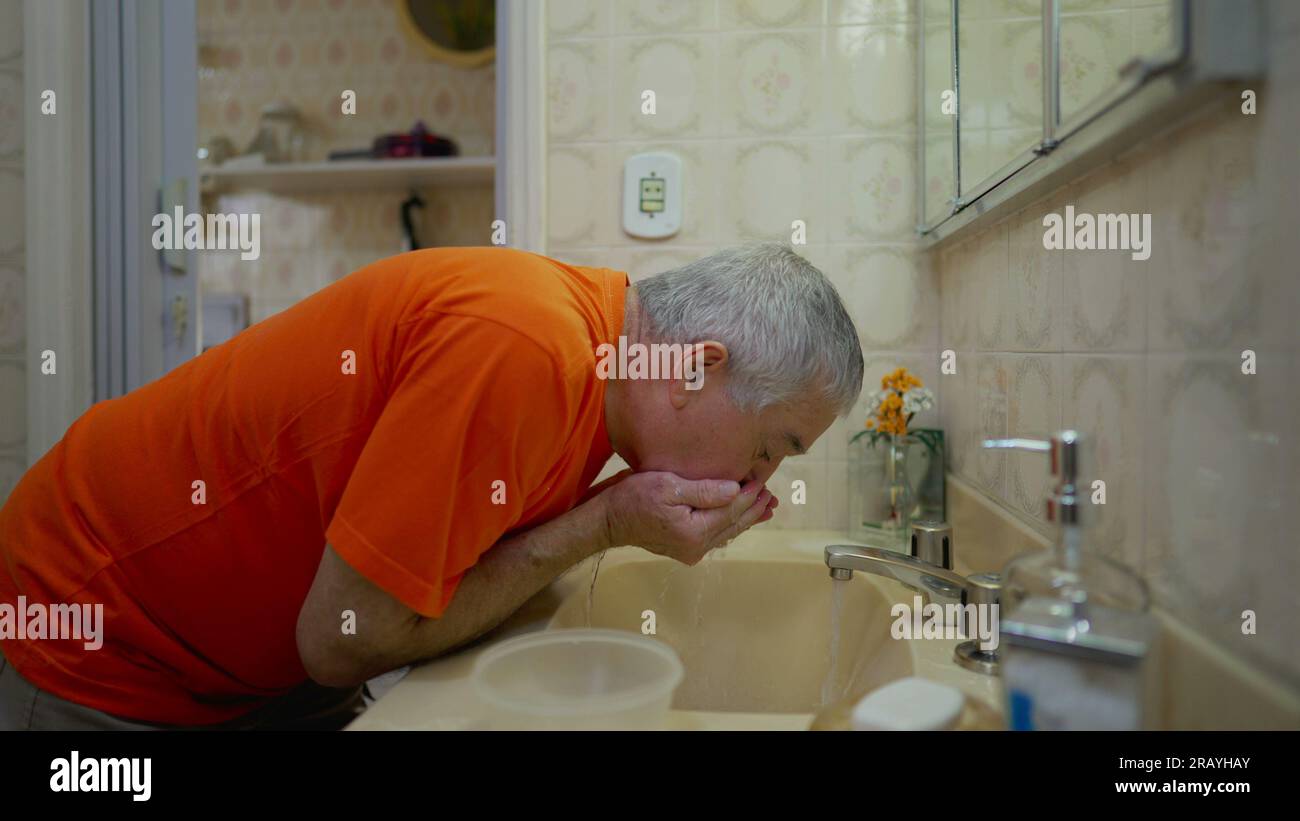 Senior man washing face in bathroom, domestic lifestyle morning routine ...