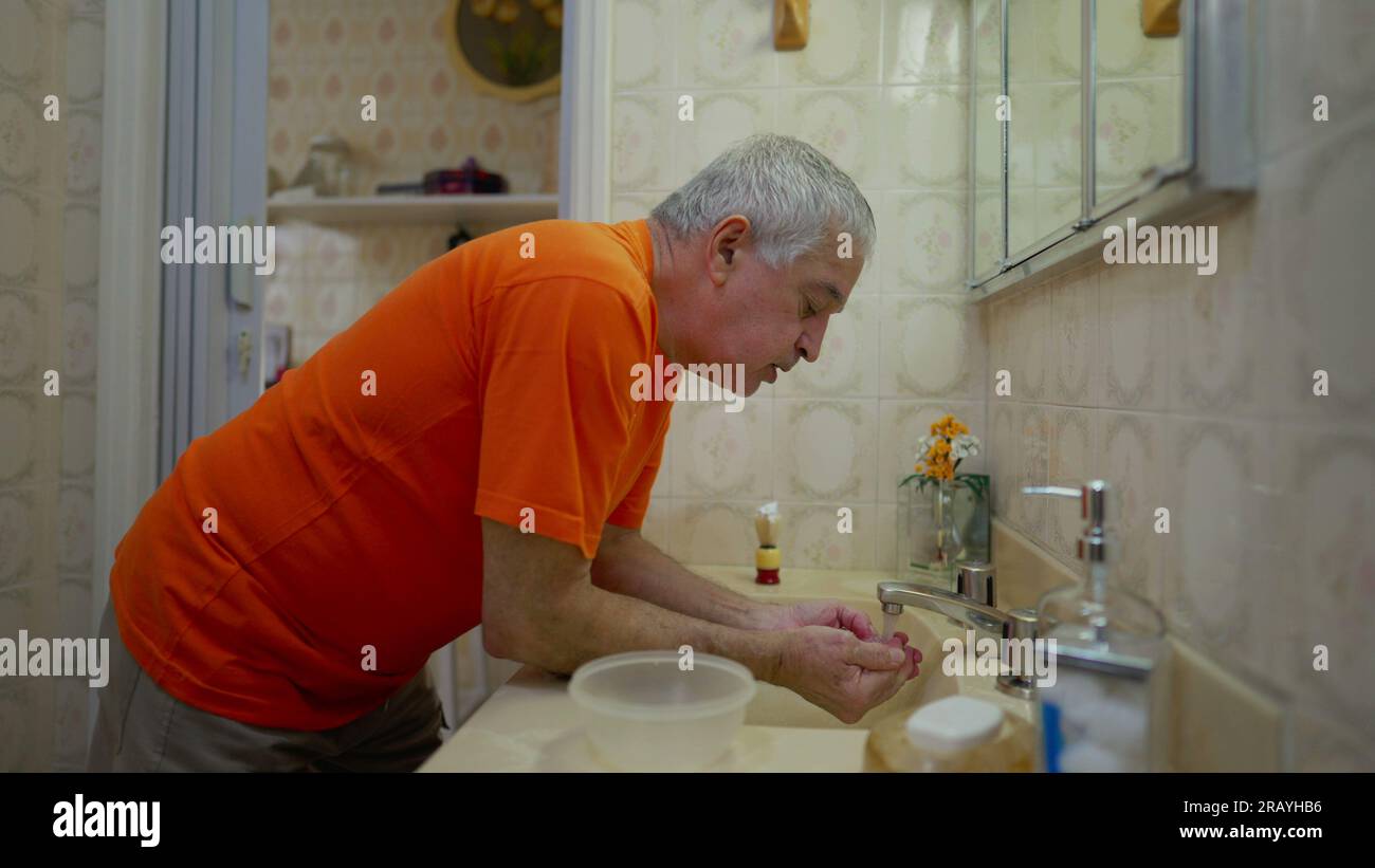 Senior man washing face in bathroom, domestic lifestyle morning routine ...