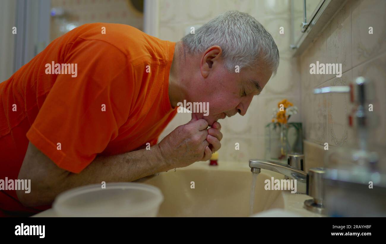 Senior man washing face in bathroom, domestic lifestyle morning routine ...