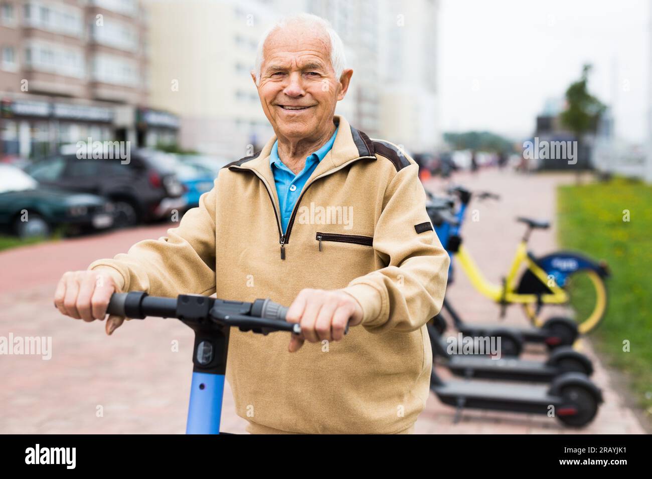 Old man riding down street on electric scooter Stock Photo - Alamy