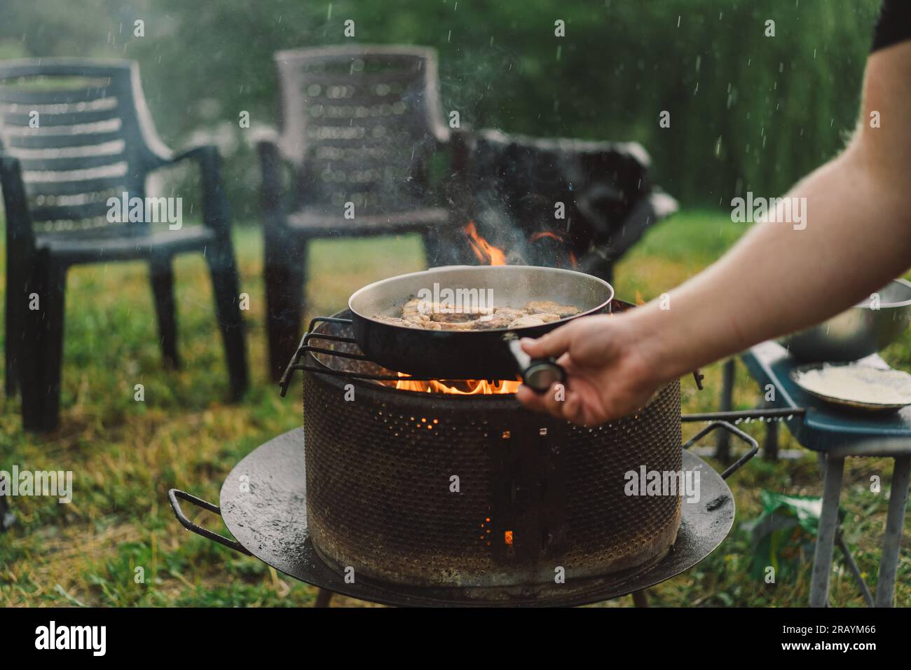 Man cooking fish on fire in nature, camping outdoors Stock Photo - Alamy