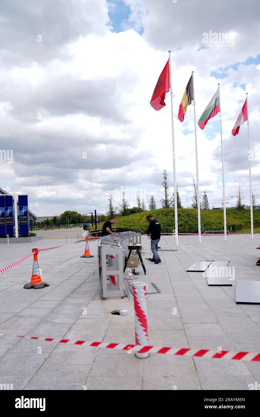 Two men do construction work around the flags at NATO headquarters in ...