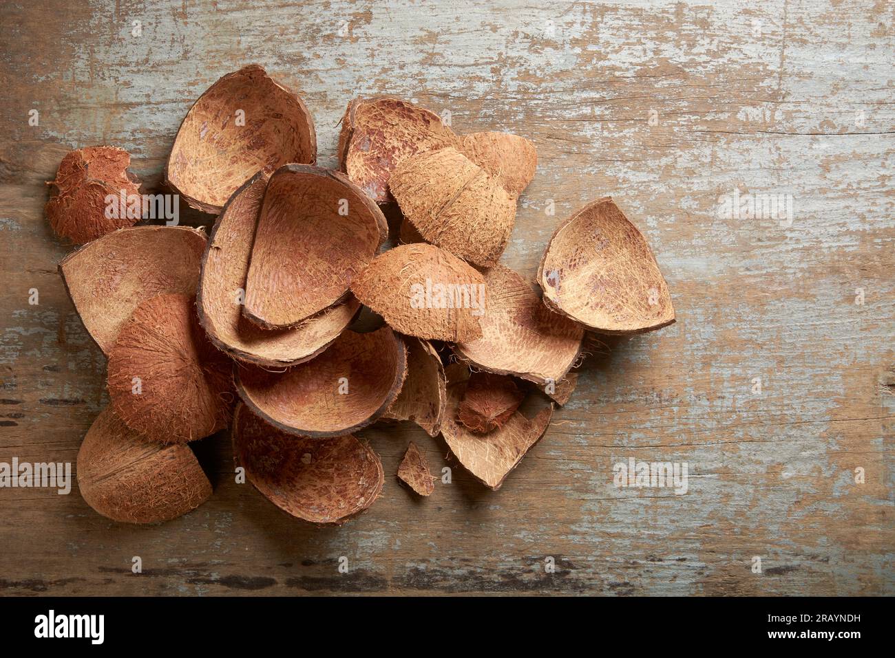 pieces of coconut fruit shell on wooden table top, pile of commercially ...