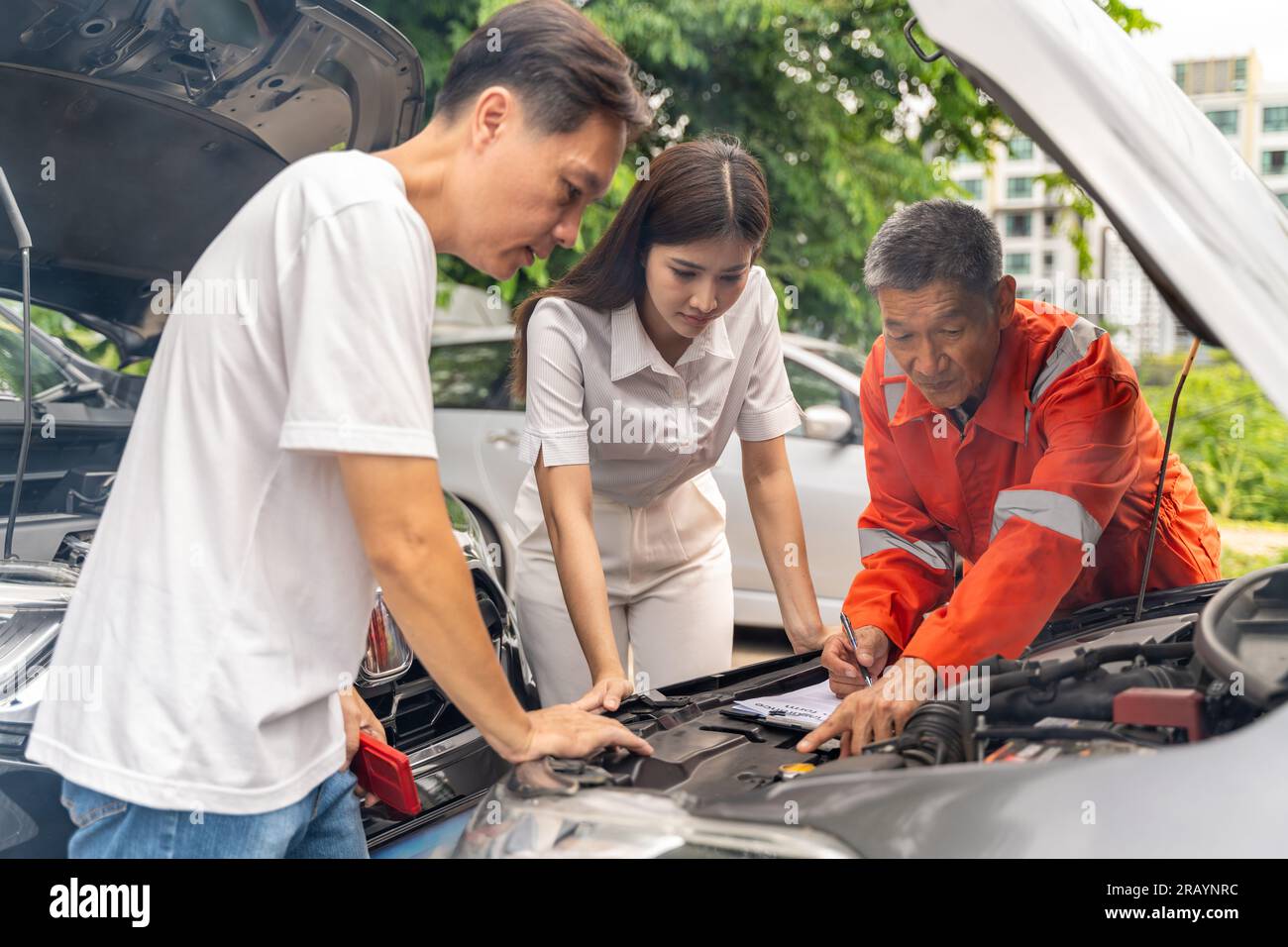 Car machanic showing the man and woman the problem of their car's ...