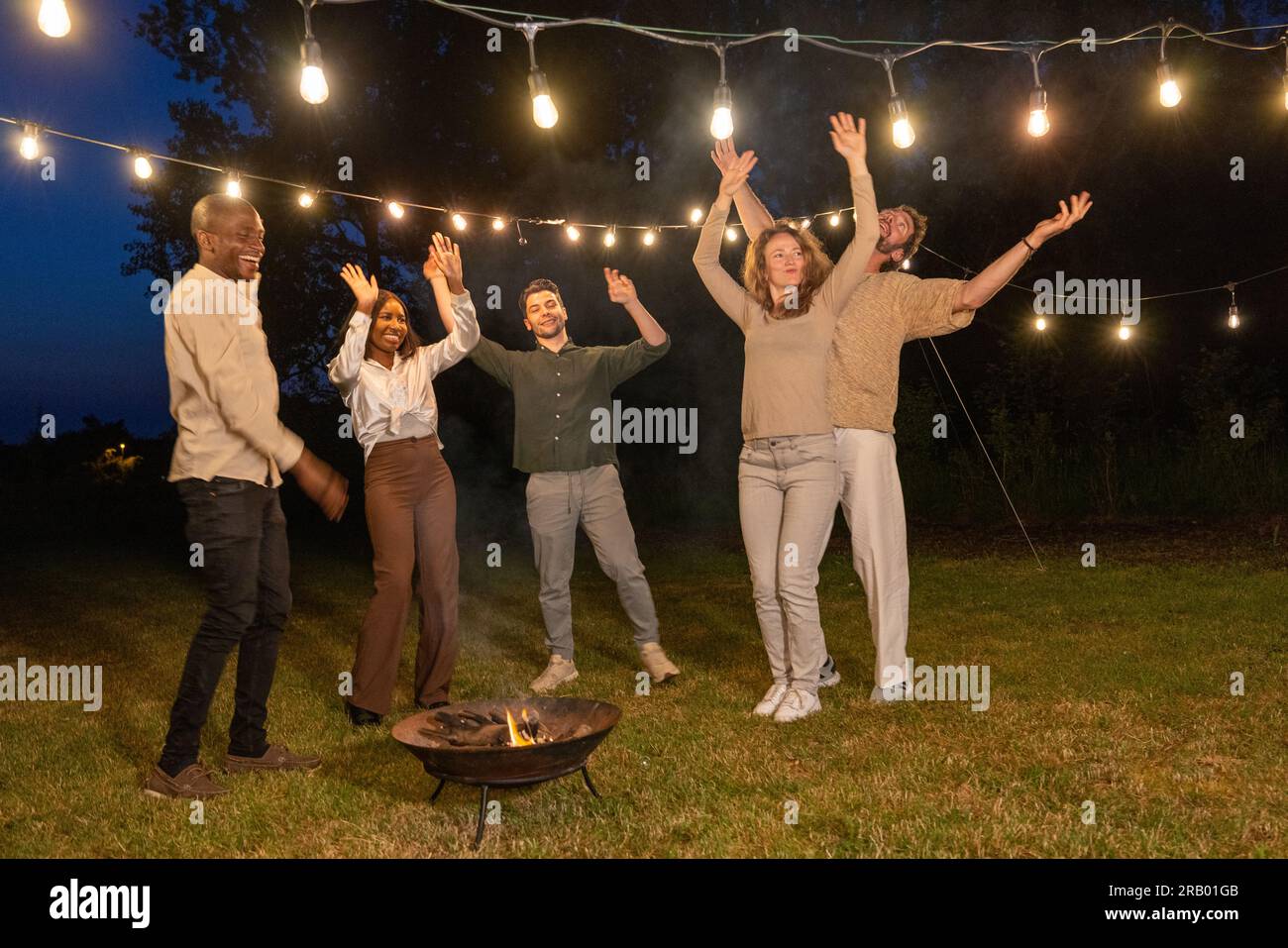 Multi ethnic group of friends having outdoor garden barbecue laughing ...