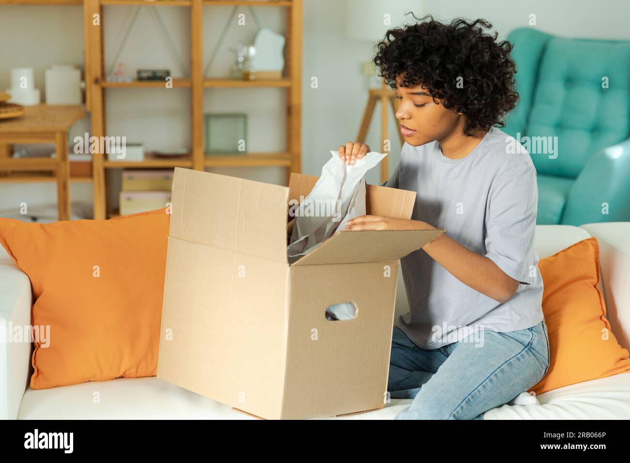 African girl unpacking delivery looking in box. Happy woman opening ...