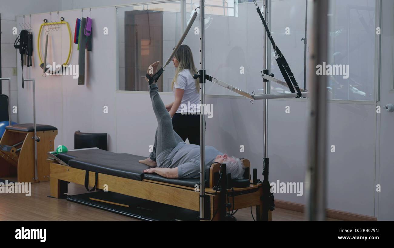 Female Pilates teacher coaching seniors in group class inside ...