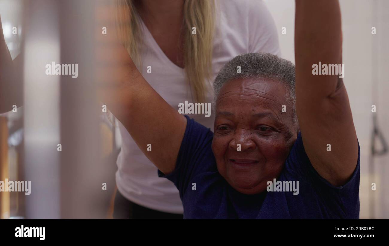 Female Sport Coach assisting a Black African American Senior woman to ...