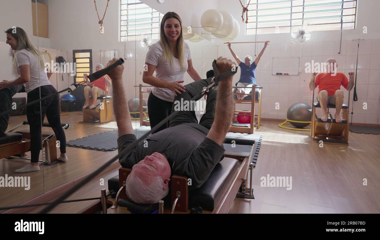 Group Pilates Session with Elderly people, Coach Assisting Senior Man ...