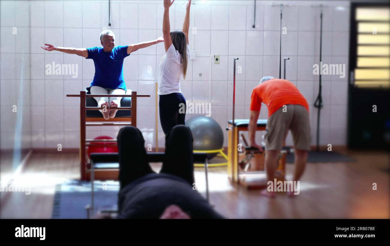 Guided Fitness Scene of Pilates Instructor Assisting Seniors in a Group ...