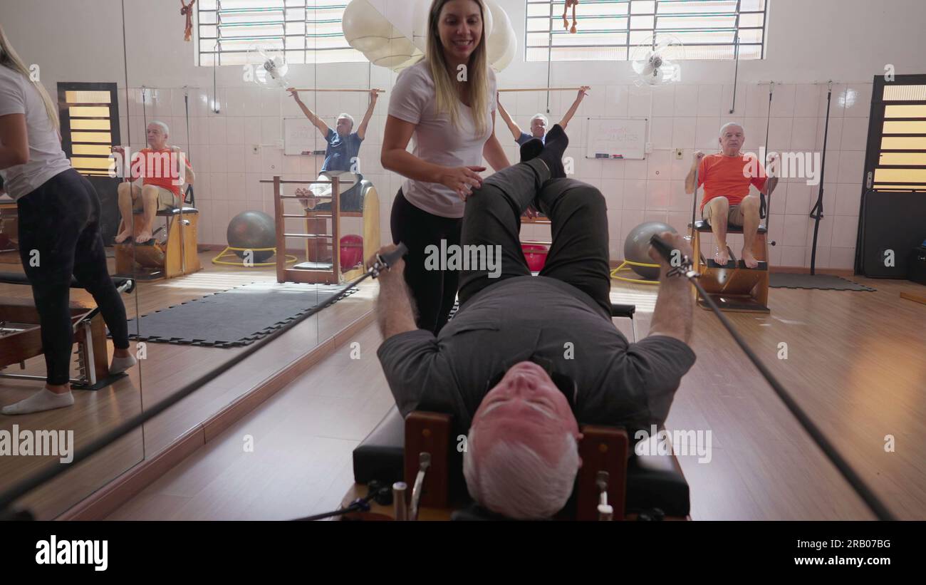 Group Pilates Session with Elderly people, Coach Assisting Senior Man ...