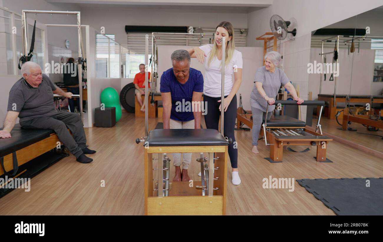 Group of elderly people doing Pilates Sessions with the help of female ...