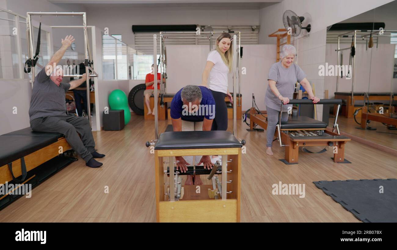 Group of elderly people doing Pilates Sessions with the help of female ...