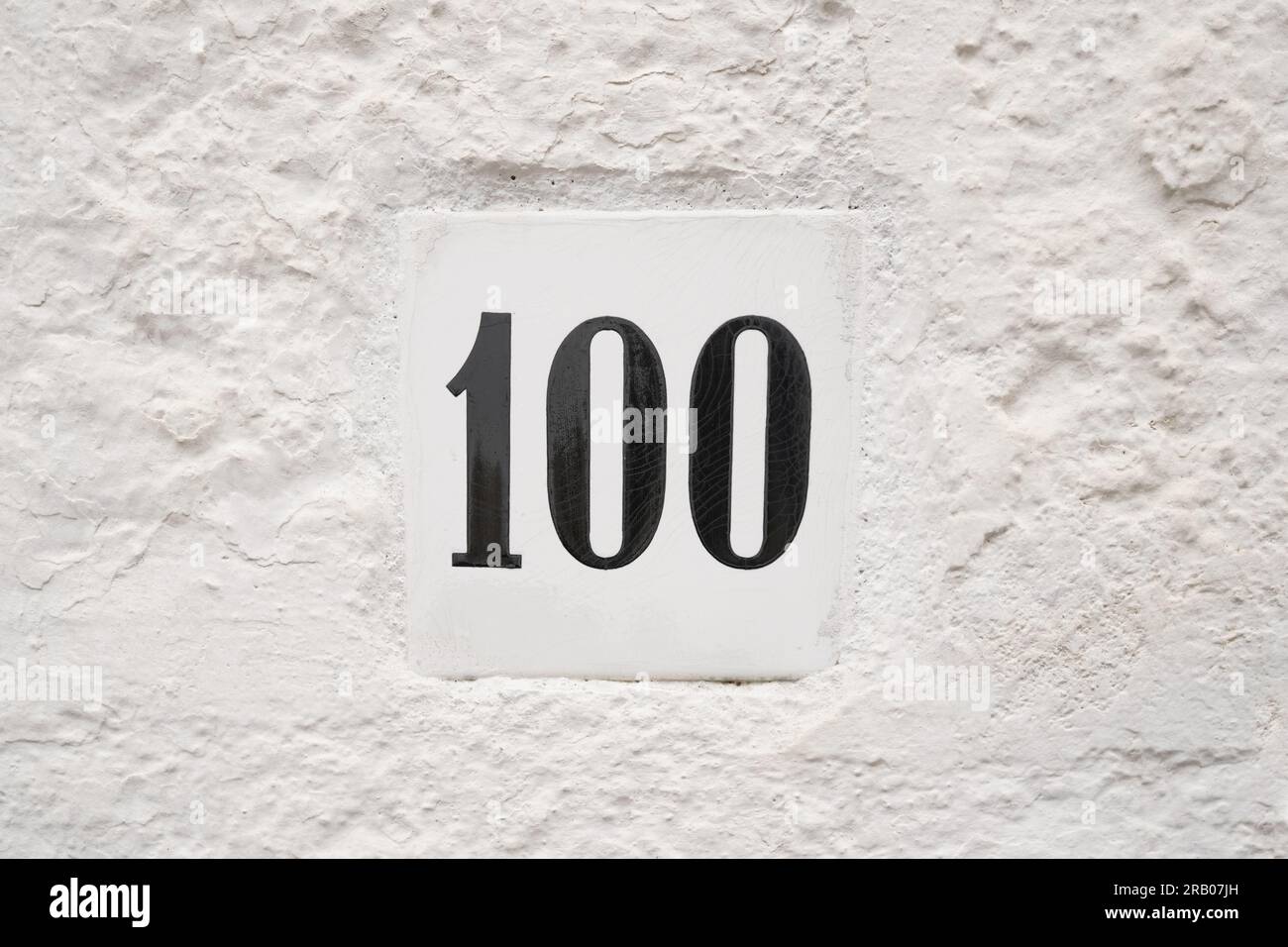 hundred ceramic number plate on white wall Stock Photo - Alamy