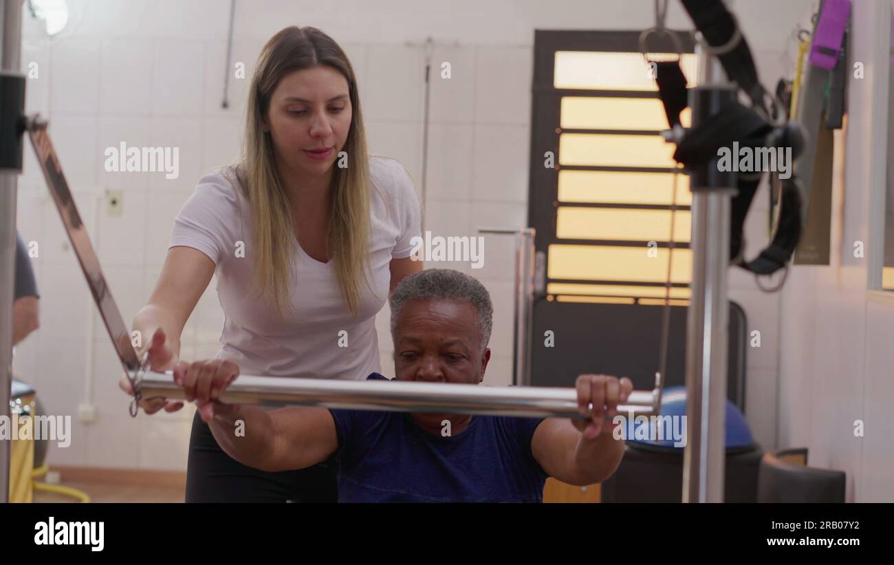 Female Pilates Coach Assisting Black Senior Woman in Machine Workout ...