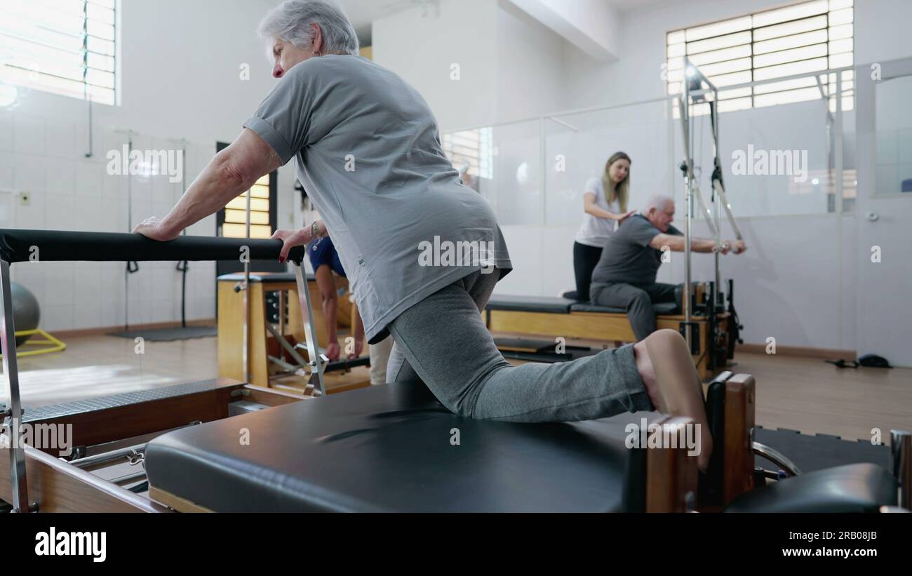 Back of senior woman using Pilates Machine to stretch body. Elderly ...