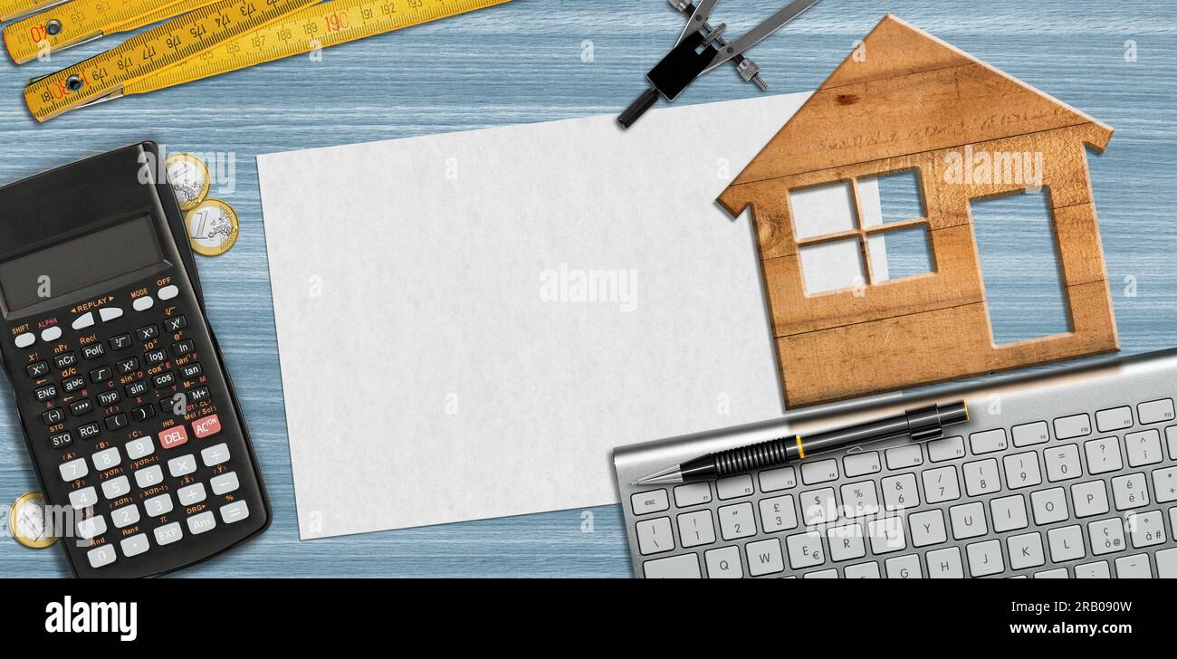 Wooden model house on a desk with blank sheet of paper, calculator ...