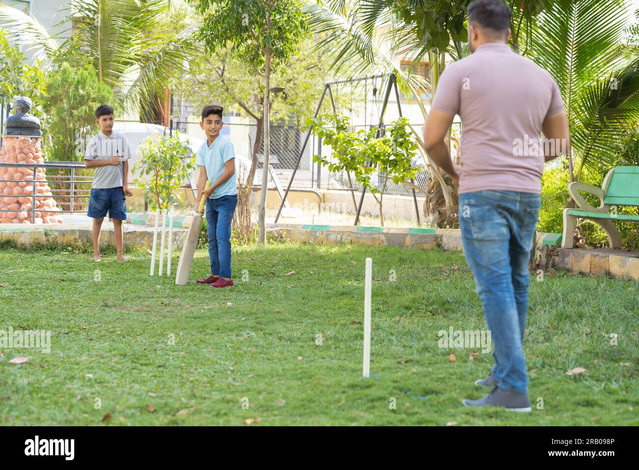 Indian joyful father with sibling kids playing cricket sports game ...
