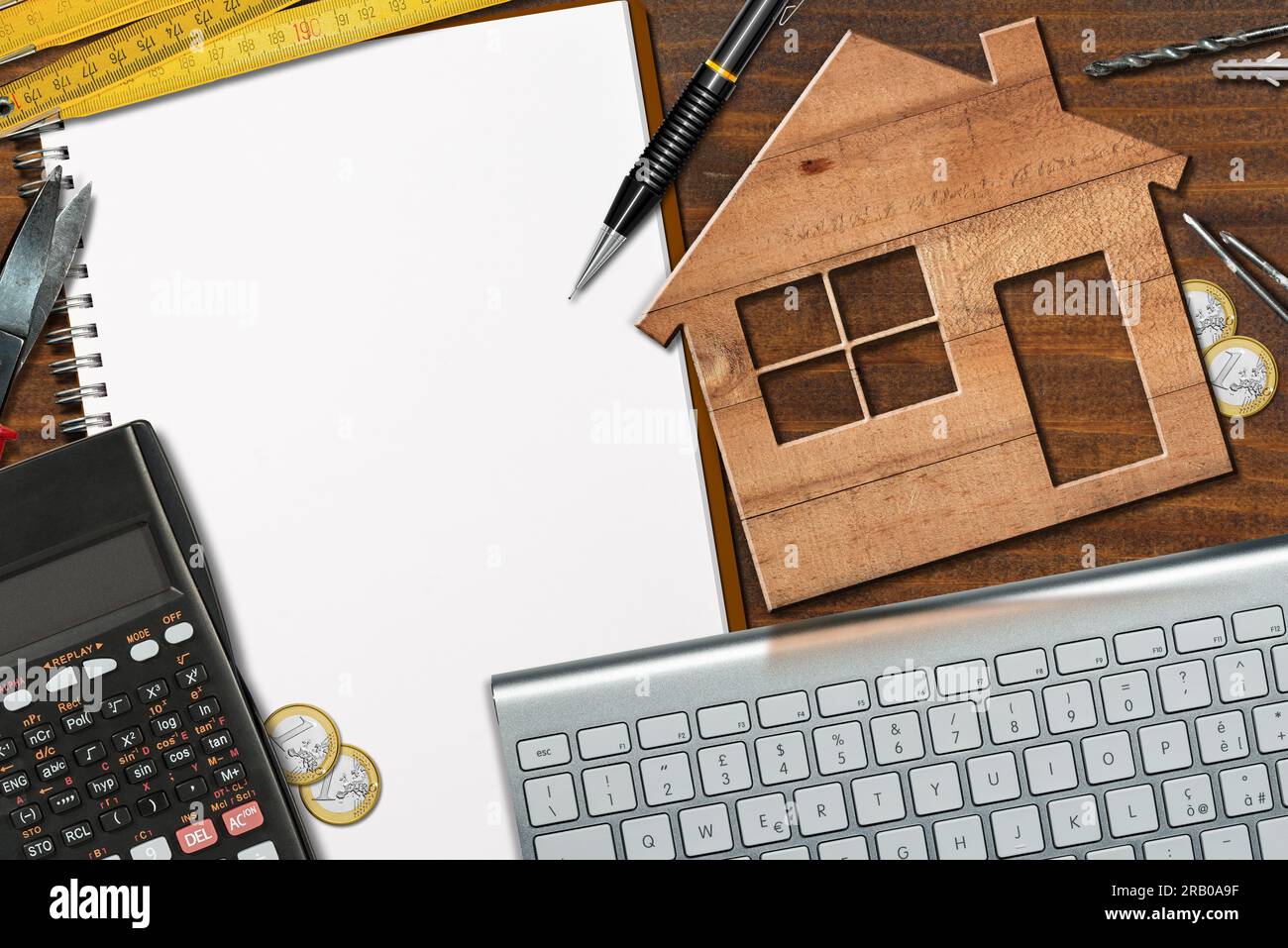 Small wooden model house on a desk with blank note book (spiral ...