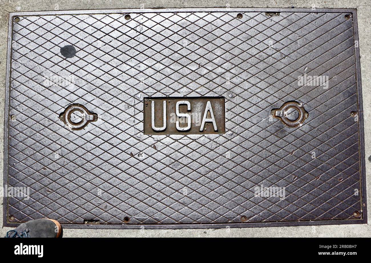 Metal manhole cover marked USA with crosshatching on the sidewalk on ...