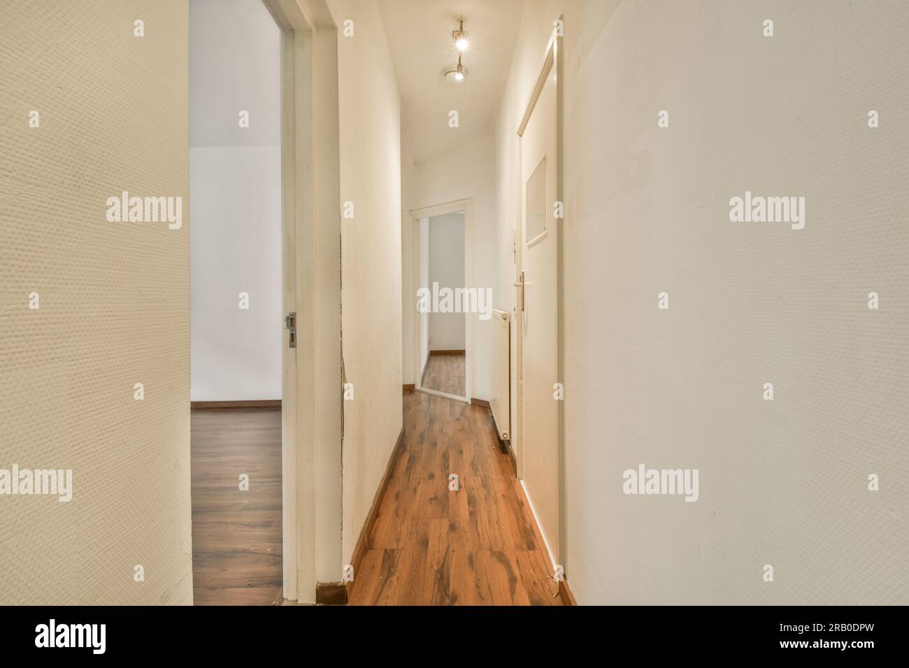 a long hallway with wood flooring and white walls on either side of the ...