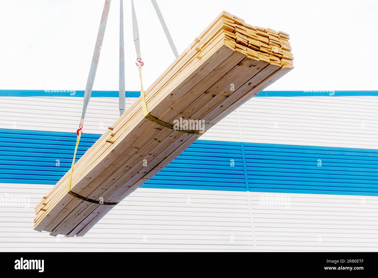 Wooden boards are lifted up on lift slings. Loading timber and building ...