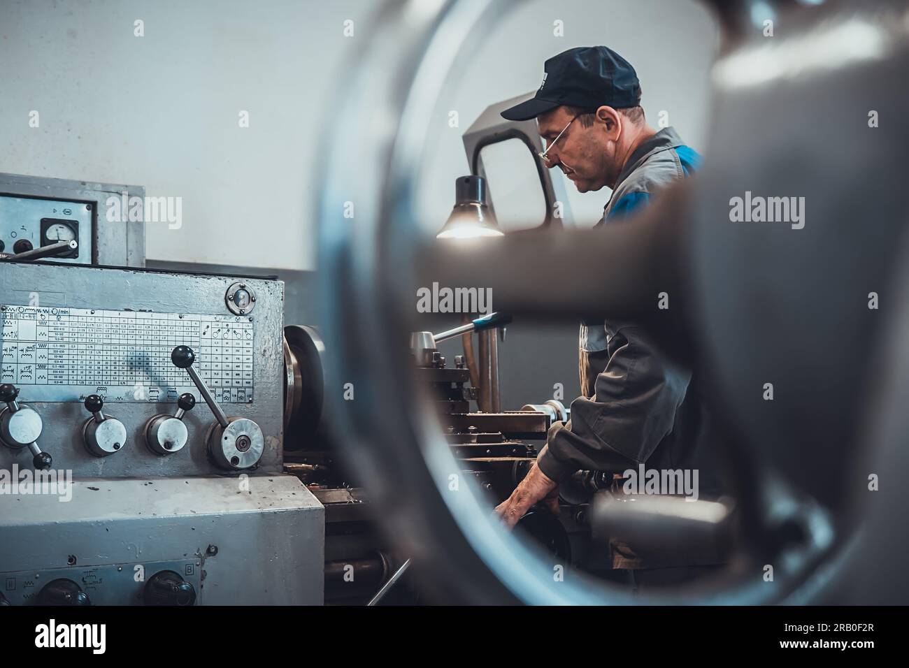 Professional metal turner works at factory on lathe. Portrait of turner ...