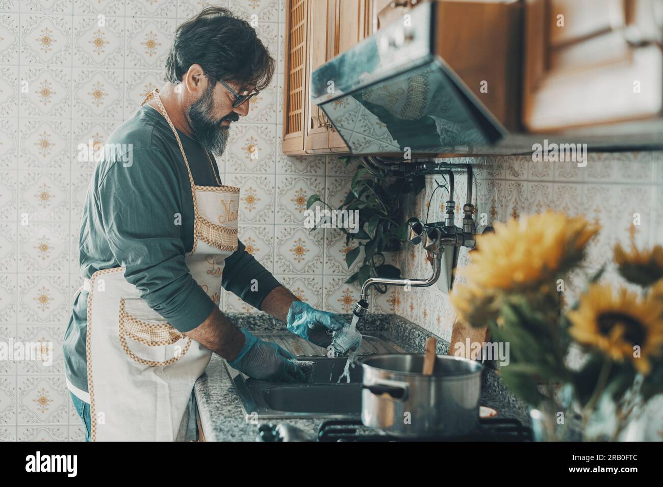 One man washing dishes at home in the kitchen after lunch time. husband ...