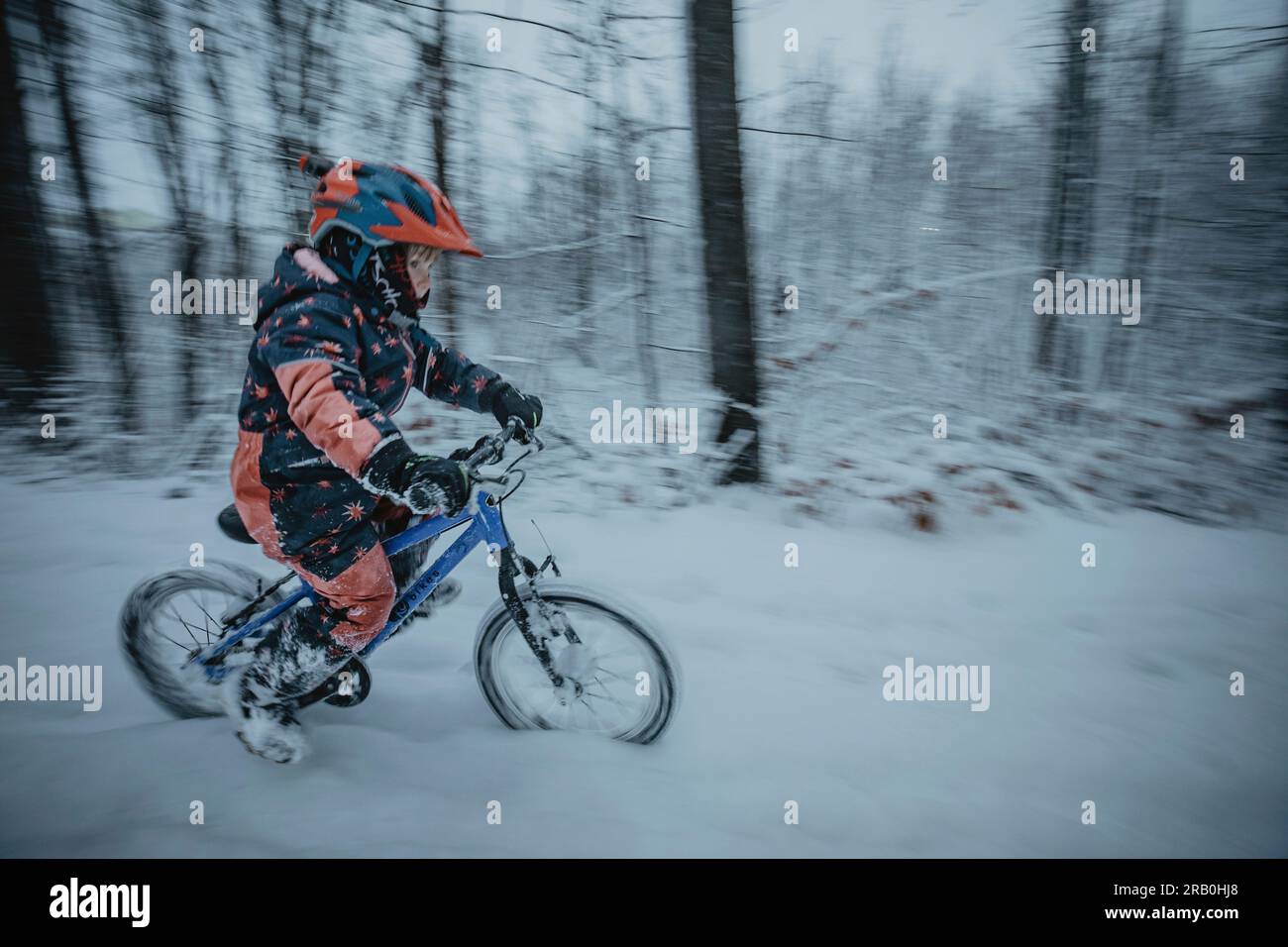 Boy riding farm bike in snowy forest Stock Photo - Alamy