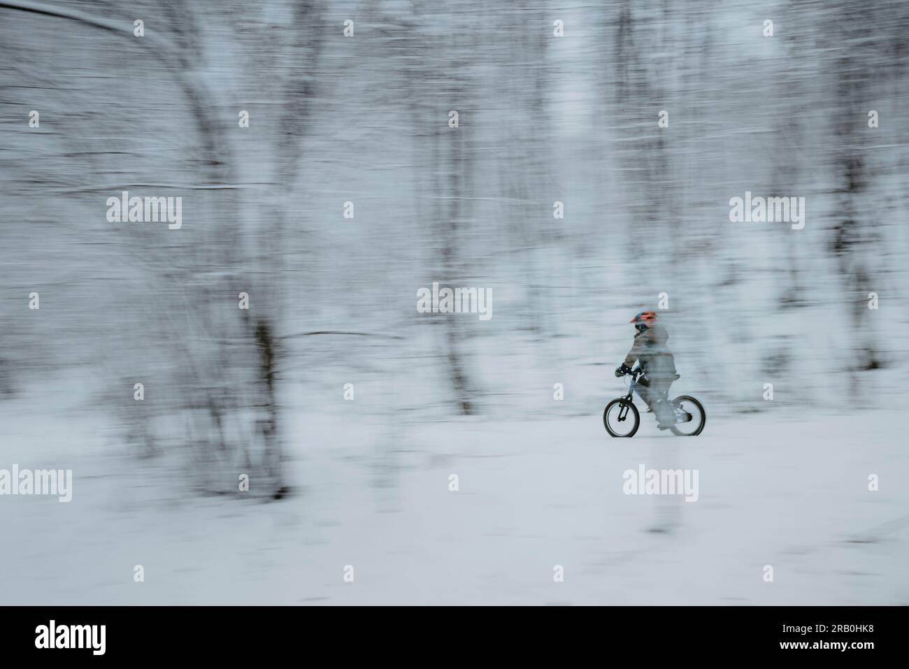 Boy riding farm bike in snowy forest Stock Photo - Alamy