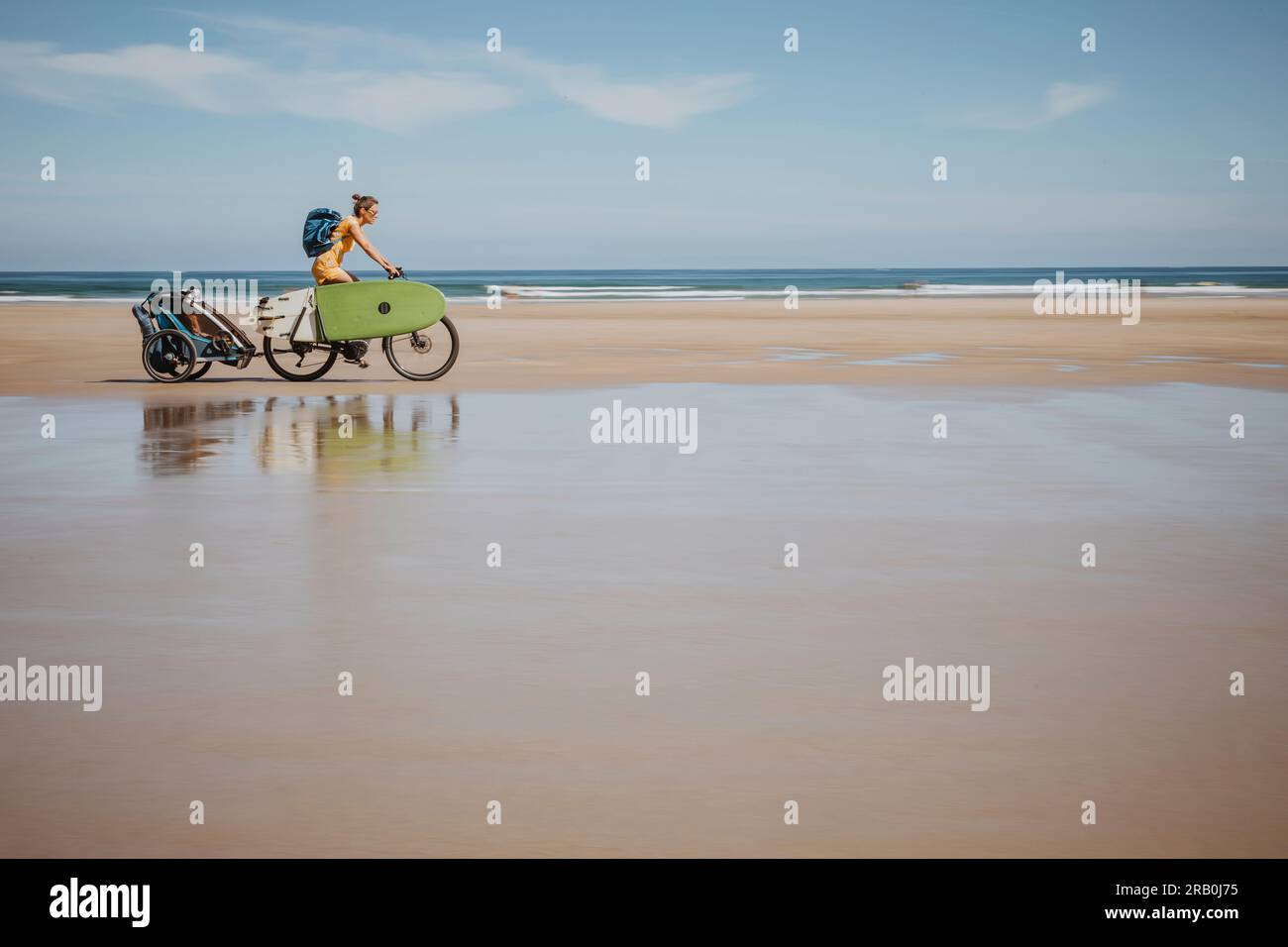 Surfer woman with bike and trailer on beach Stock Photo - Alamy