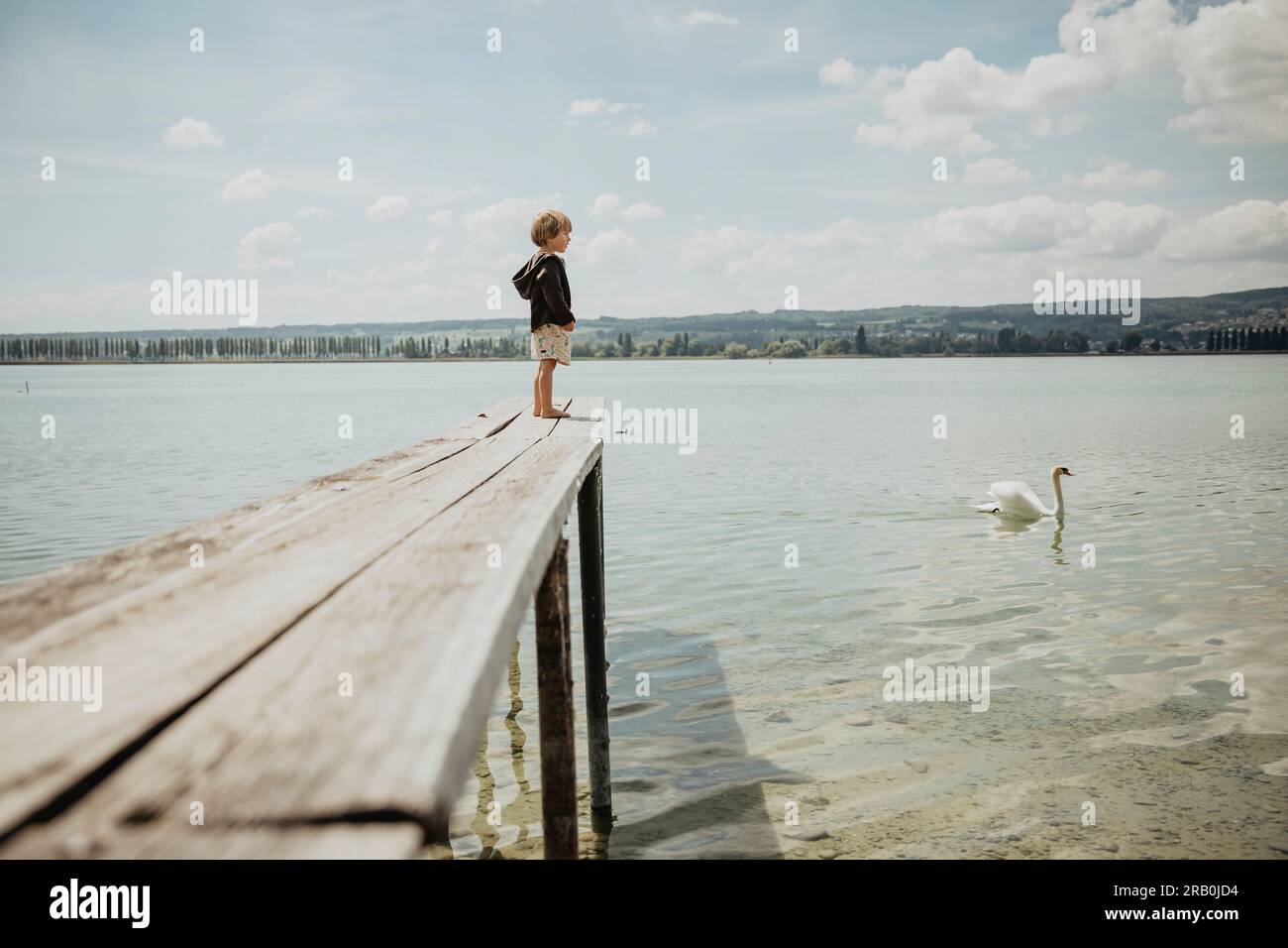 Little boy on a jetty by the lake Stock Photo - Alamy