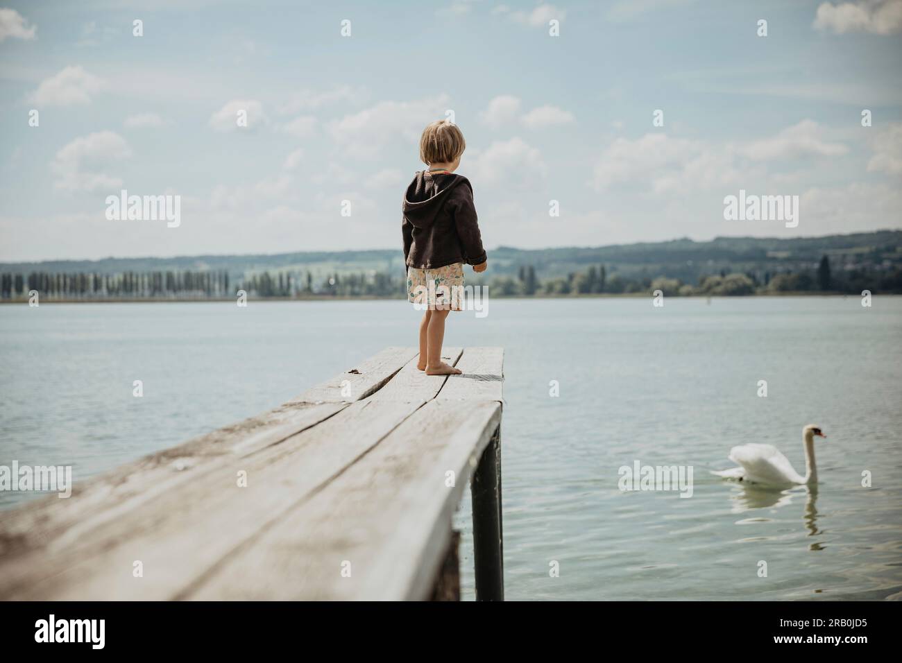 Little boy on a jetty by the lake Stock Photo - Alamy