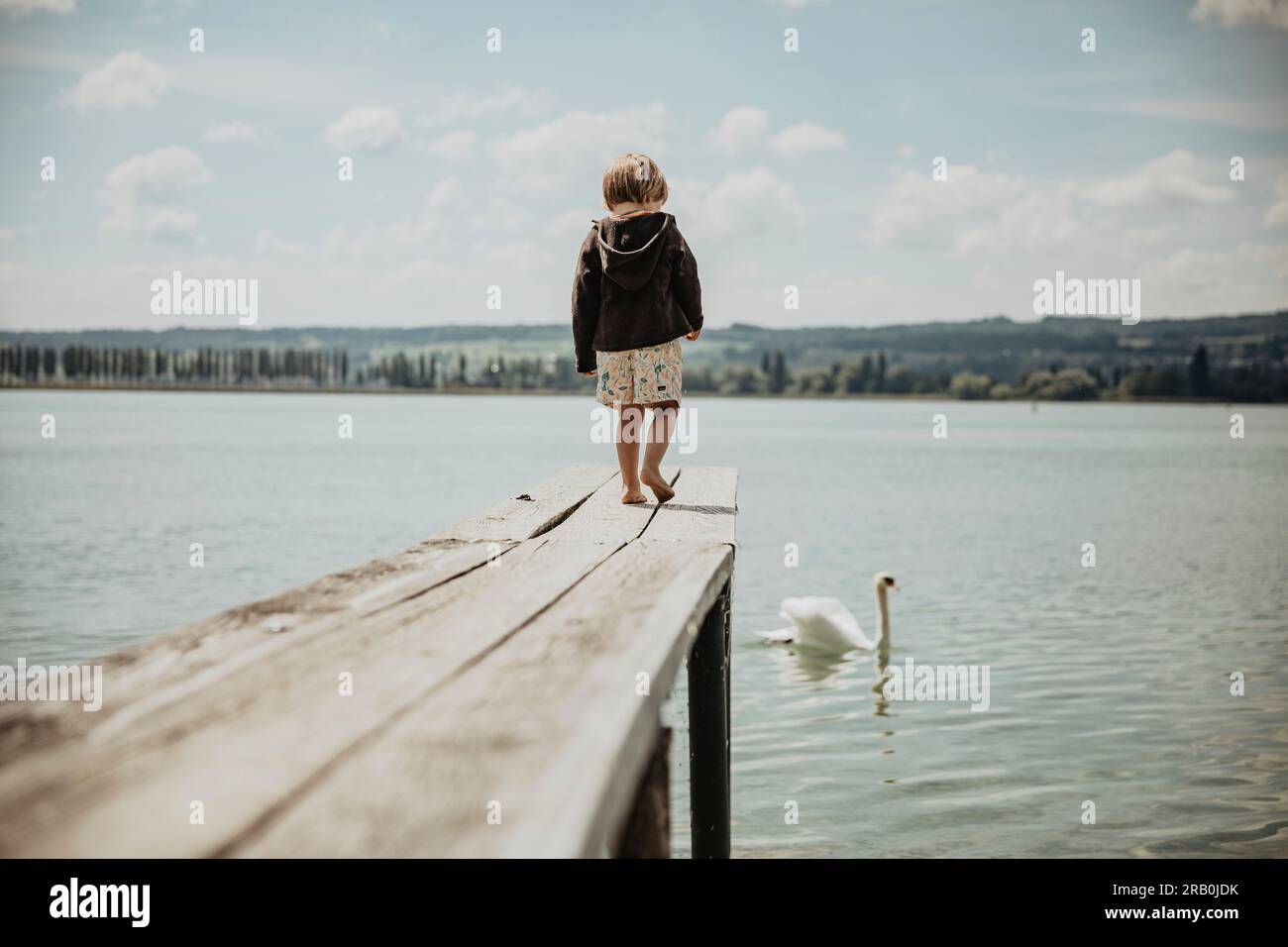 Little boy on a jetty by the lake Stock Photo - Alamy