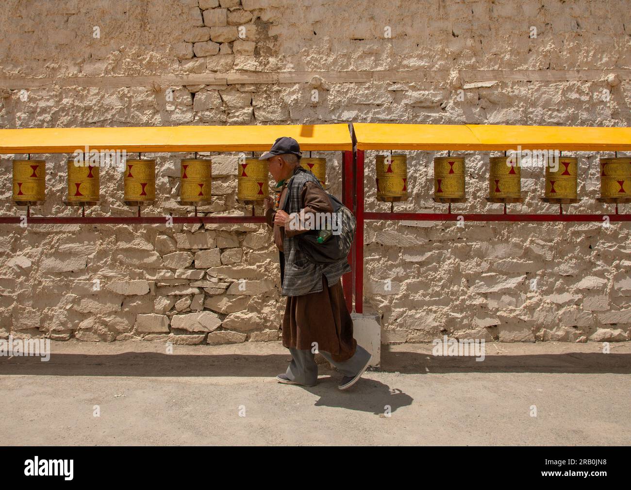 Pilgrim in front of prayer wheels in Lamayuru Monastery, Ladakh ...