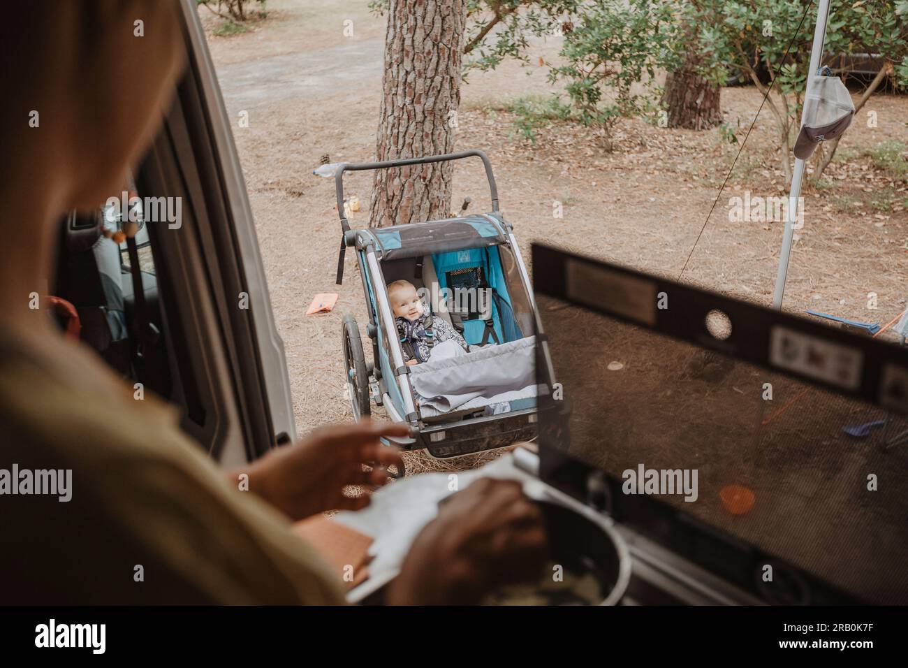 Mother cooking in camper and looking at daughter in stroller Stock ...