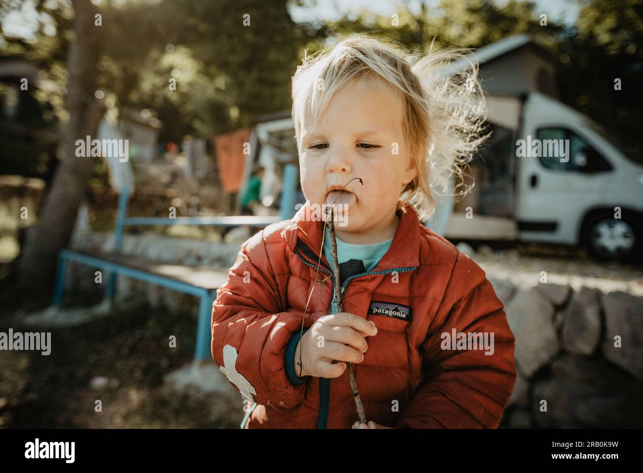 Girl playing with stick at campsite Stock Photo - Alamy