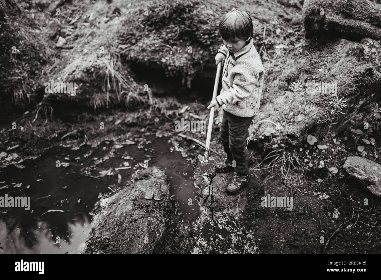 Boy playing with shovel at stream Stock Photo - Alamy