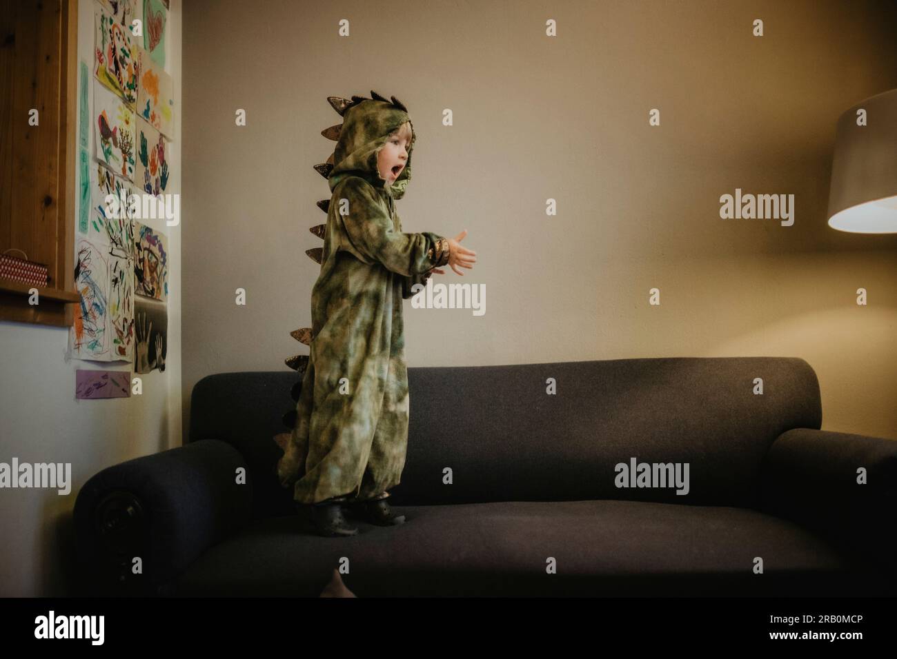 Boy in dinosaur costume standing on sofa Stock Photo - Alamy