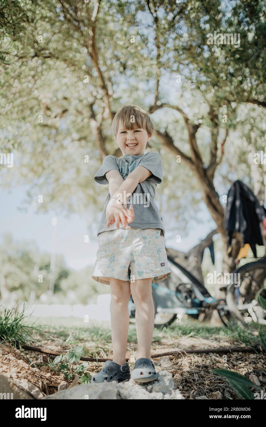 Boy standing under tree smiling Stock Photo - Alamy