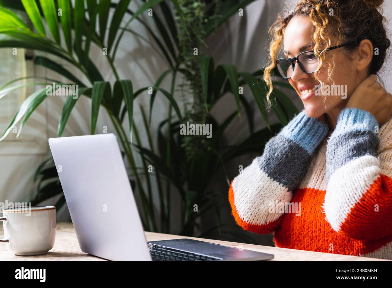 Happy woman smile and look at laptop screen touching her neck. Modern ...