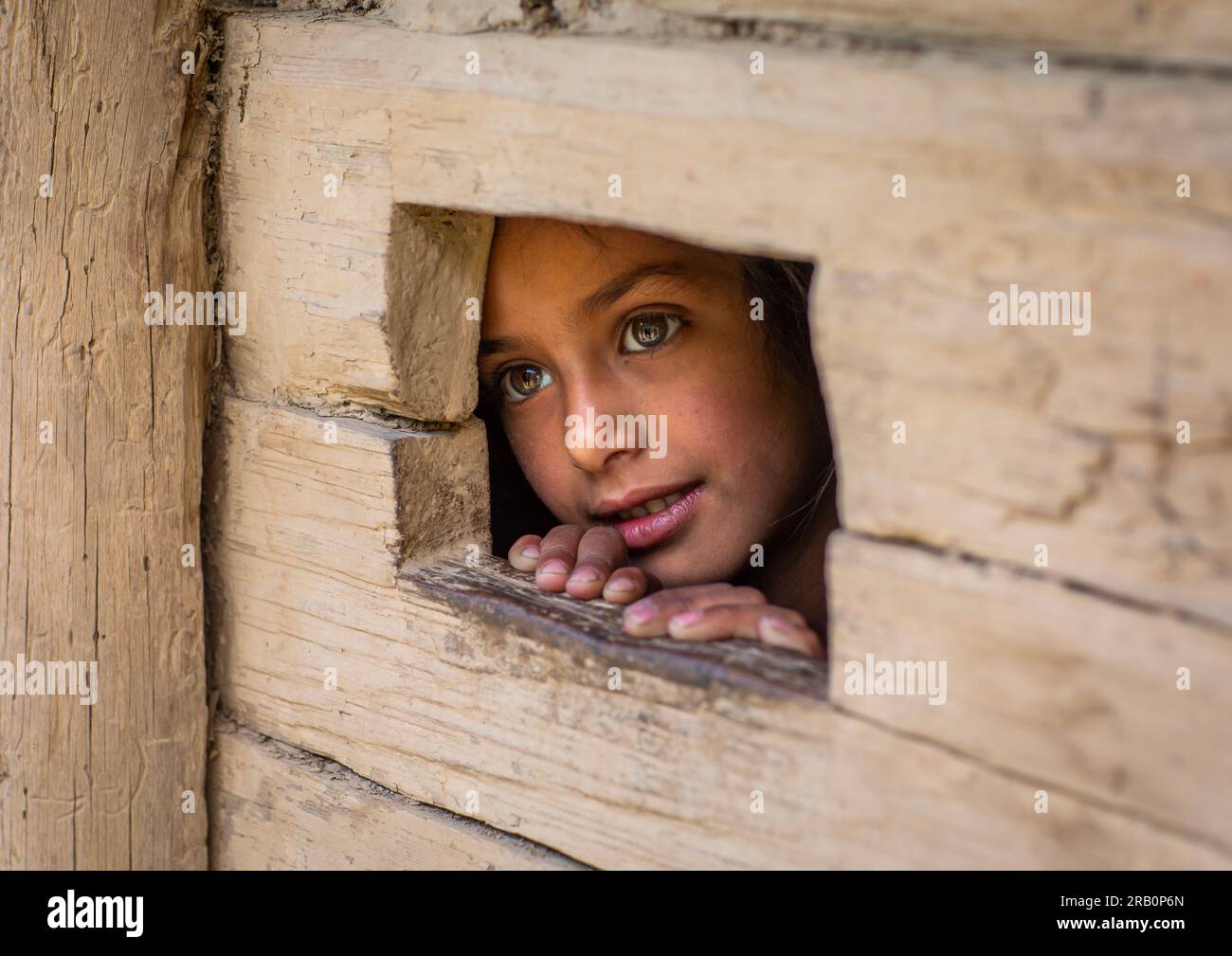 Gujjar Bakerwal girl looking through a hole in a house, Jammu and ...