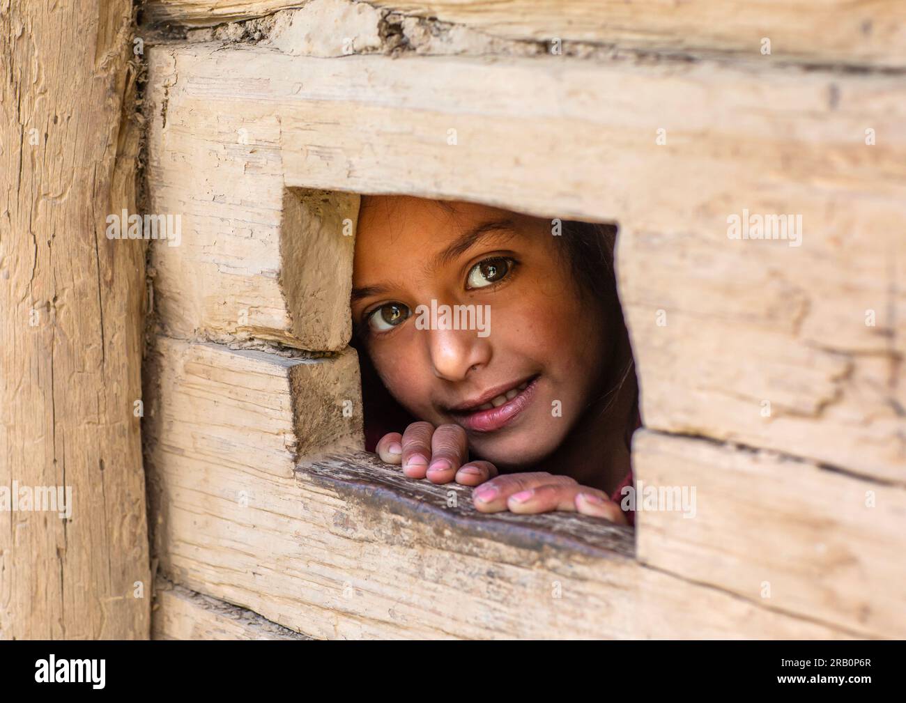 Gujjar Bakerwal girl looking through a hole in a house, Jammu and ...