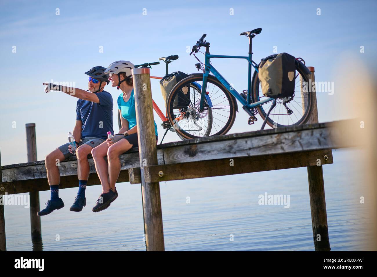 Couple, man and woman touring with bicycles, trekking bike, resting on jetty Stock Photo - Alamy