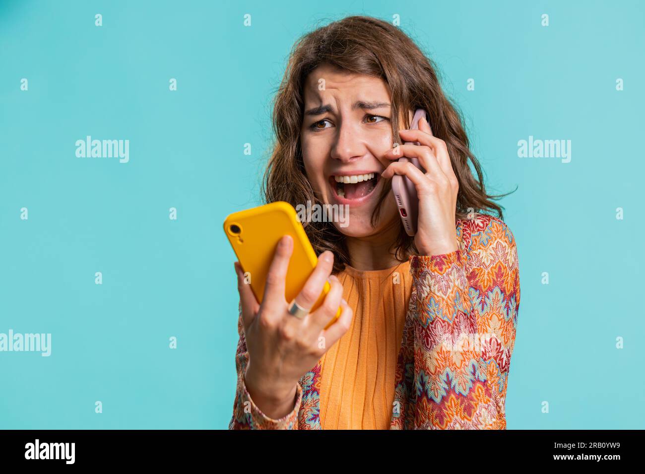 Irritated nervous stressed young woman talking screaming on two mobile ...