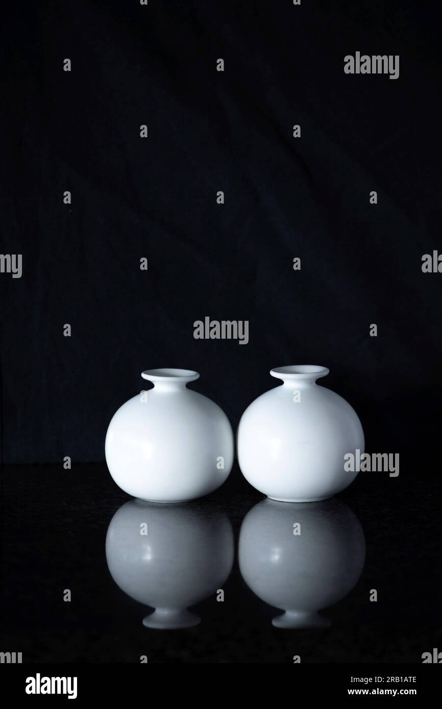 Two white round vases, black background Stock Photo - Alamy