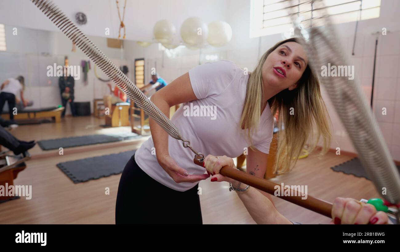 Happy Pilates coach instructing a senior woman to strengthen body with ...