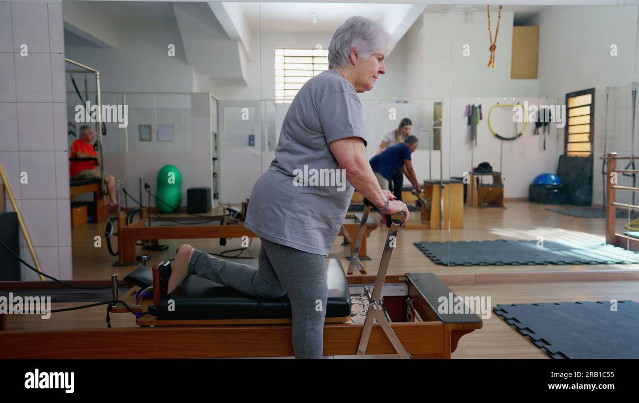 Older woman using Pilates Machine to stretch body. Elderly person ...